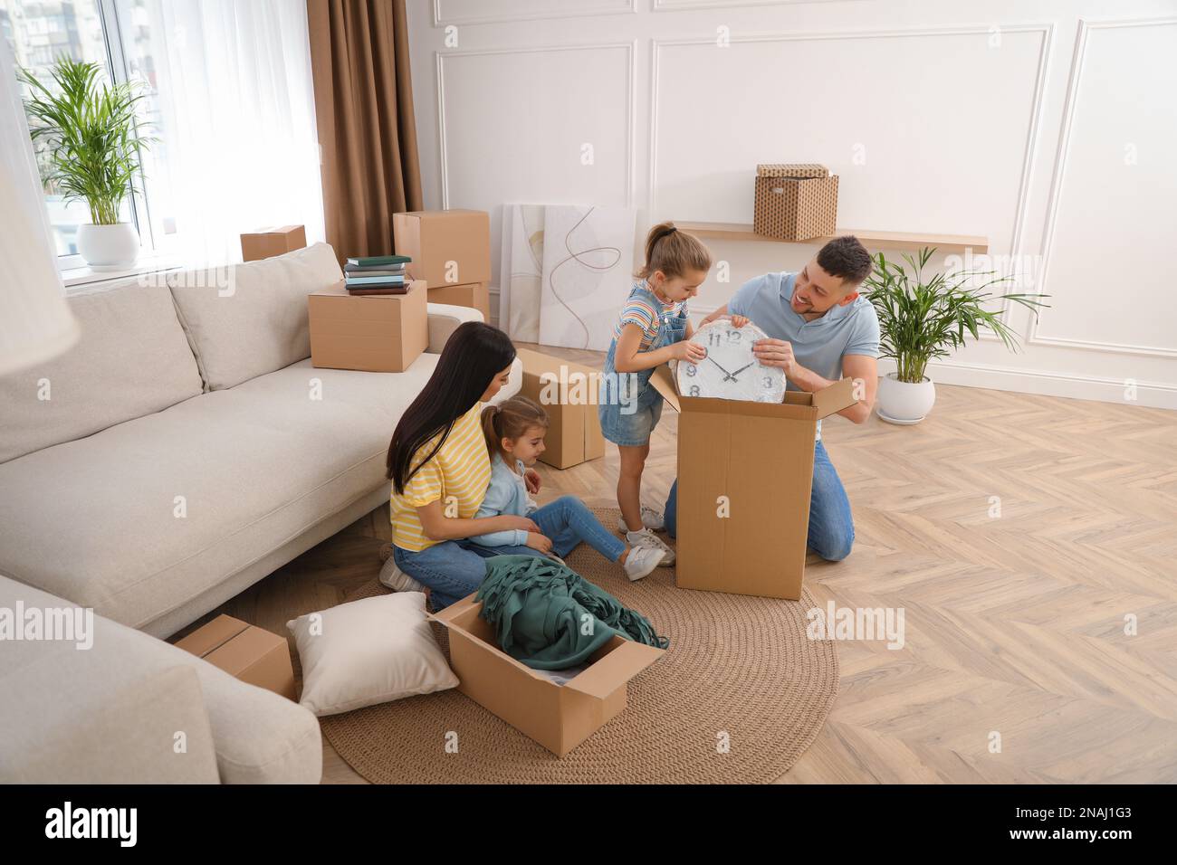 Happy family unpacking moving boxes at their new house Stock Photo - Alamy