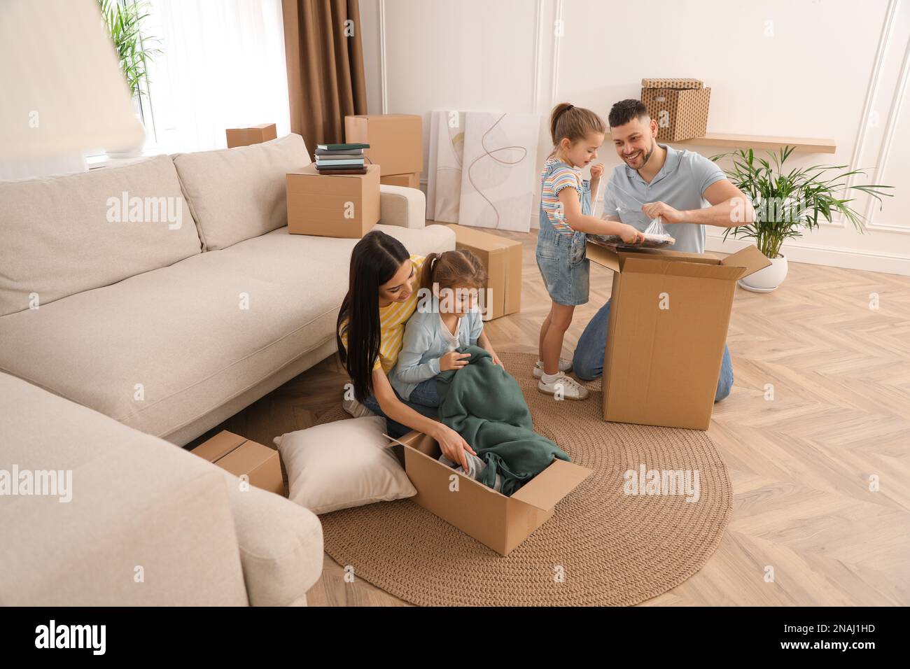 Happy family unpacking moving boxes at their new house Stock Photo - Alamy