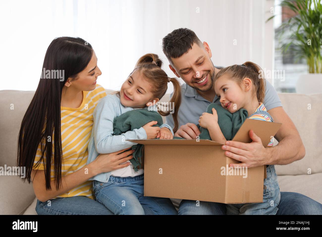 Happy family unpacking moving box at their new house Stock Photo - Alamy