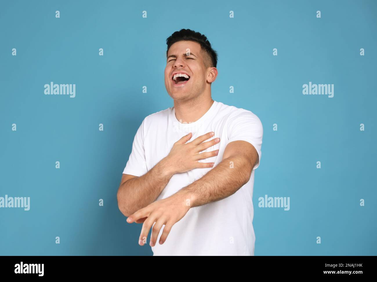 Handsome man laughing on light blue background. Funny joke Stock Photo ...