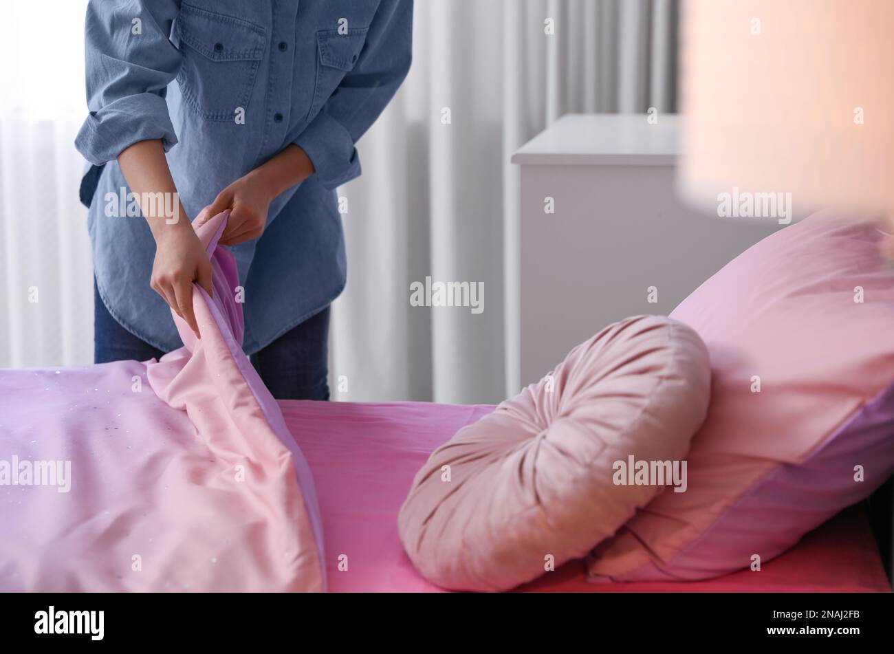 Woman making bed with new linens in children's room, closeup. Modern ...