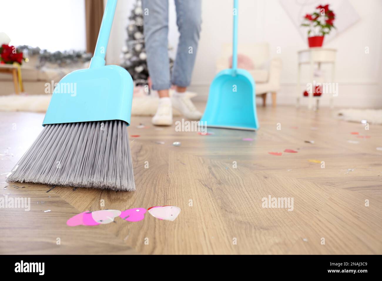 Woman cleaning messy room after New Year party, focus on broom Stock ...