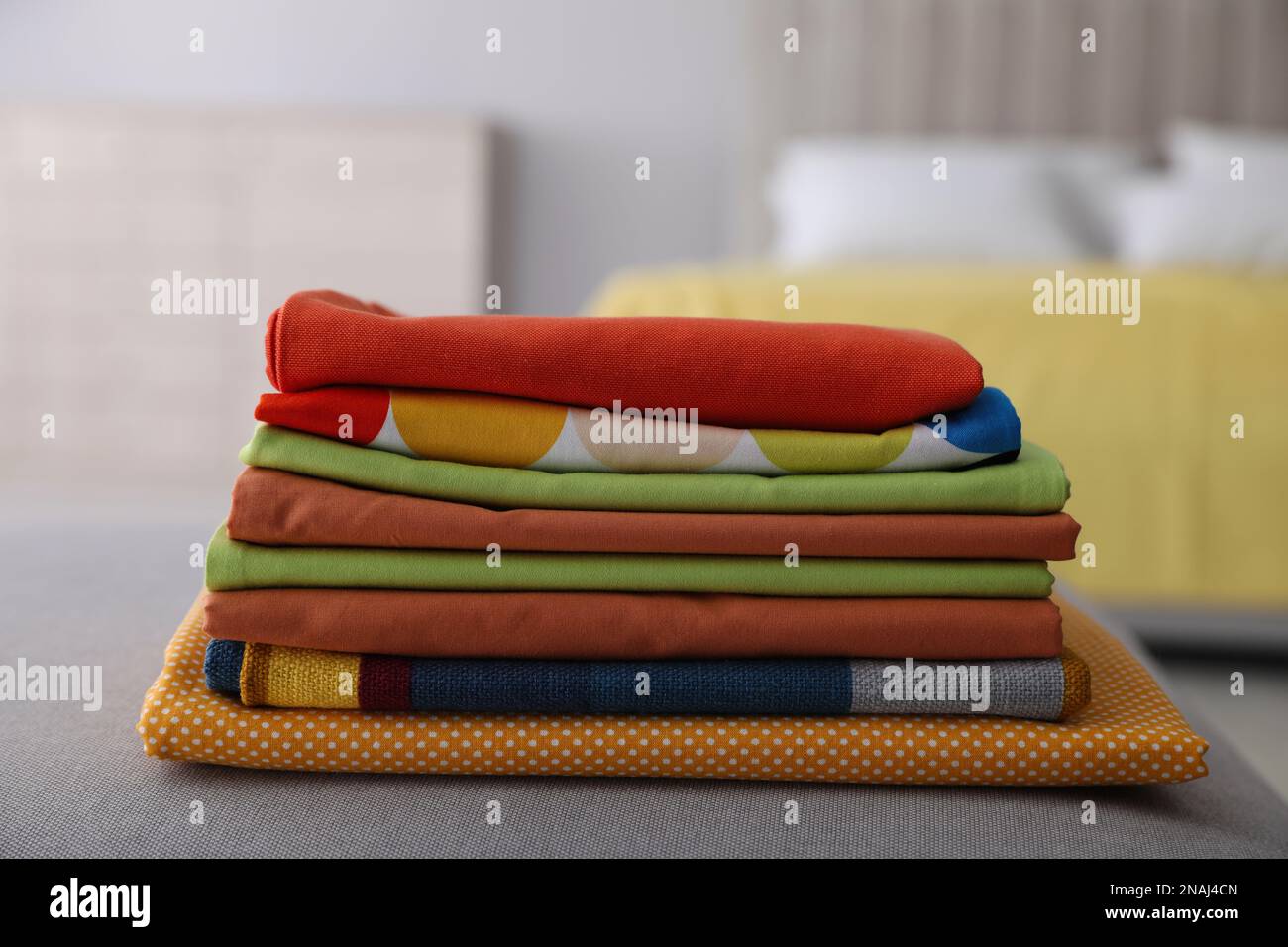 Stack of new clean folded bed linens on bench Stock Photo - Alamy