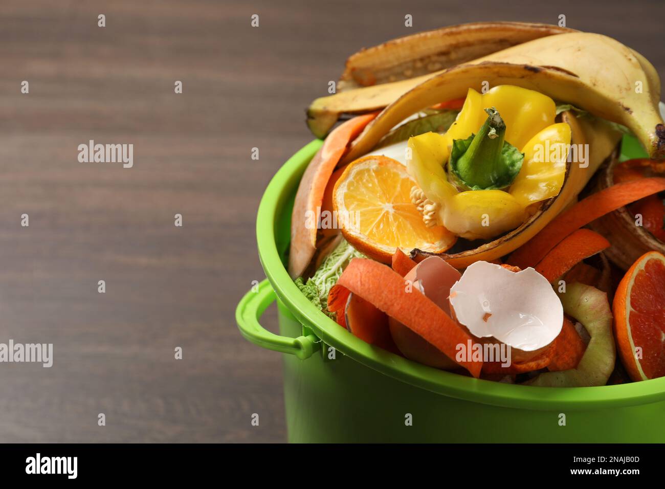 Natural garbage in trash bin on wooden background, closeup with space ...