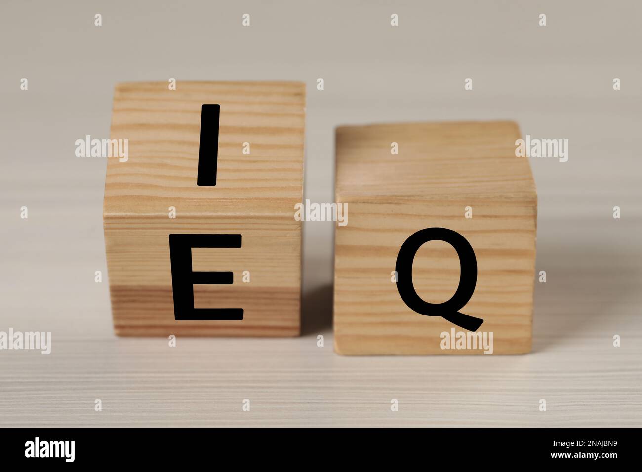 Wooden cubes with letters E, I and Q on white table Stock Photo - Alamy