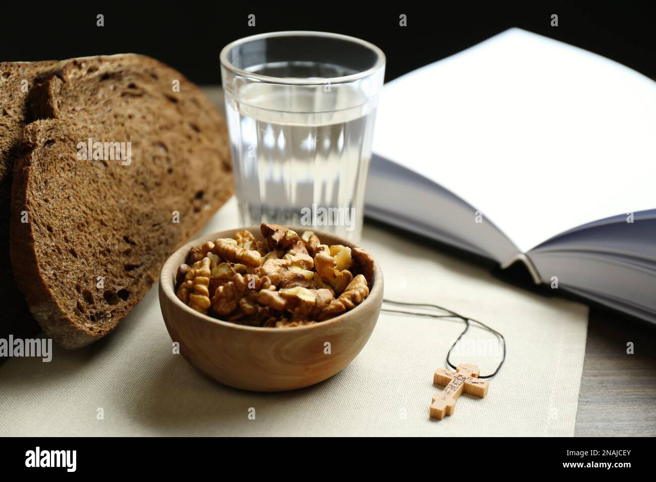 Bread, walnuts, water, Bible and crucifix on table. Great Lent season ...