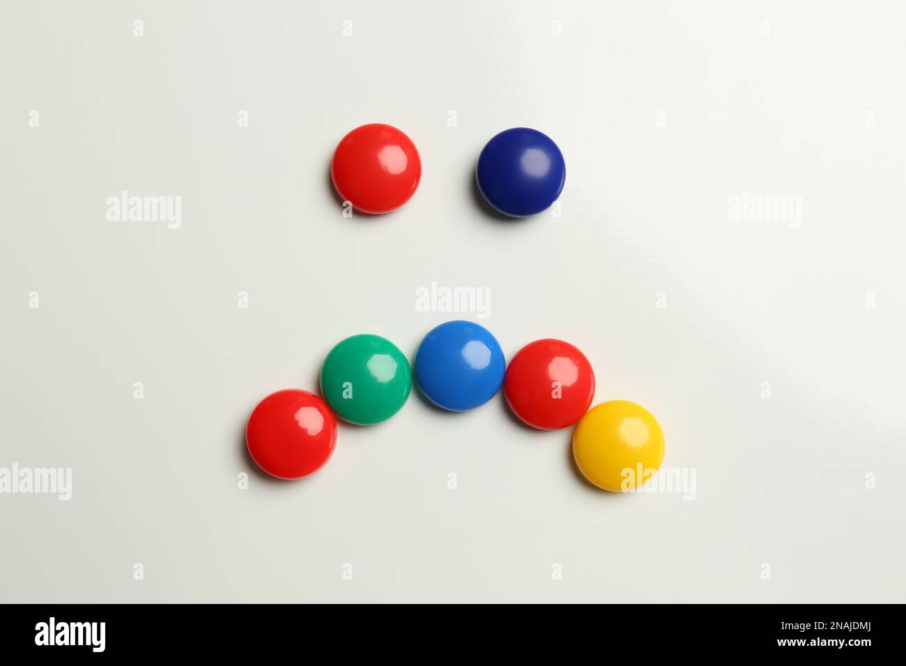 Sad face made with colorful magnets on white background, flat lay Stock ...