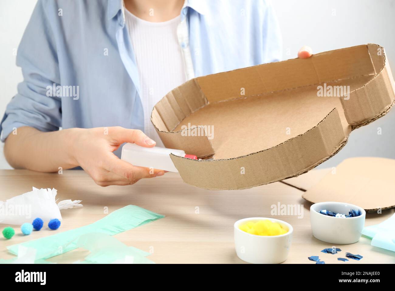 Woman making cardboard cloud at wooden table, closeup. Pinata diy Stock ...