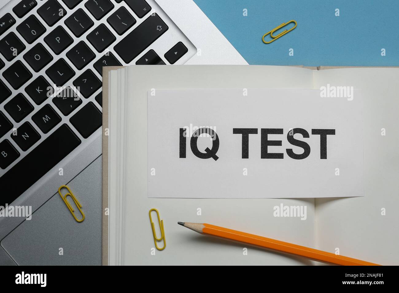 Note with text IQ Test, notebook, pencil and laptop on light blue ...