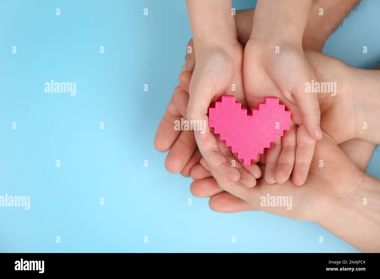 Top view of parents and kid holding pink heart in hands on turquoise ...