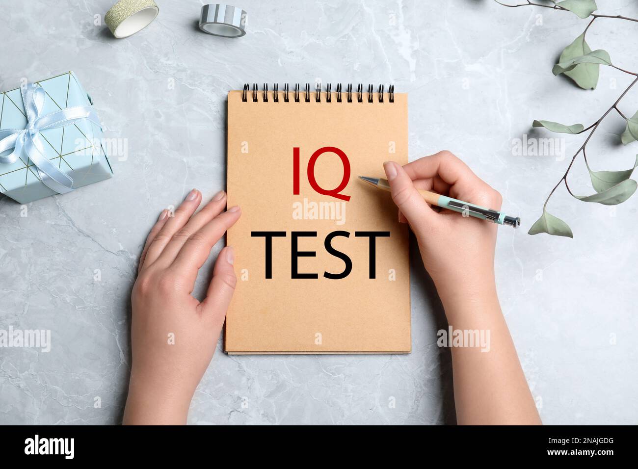 IQ Test. Woman with pen and notebook at grey table, top view Stock ...