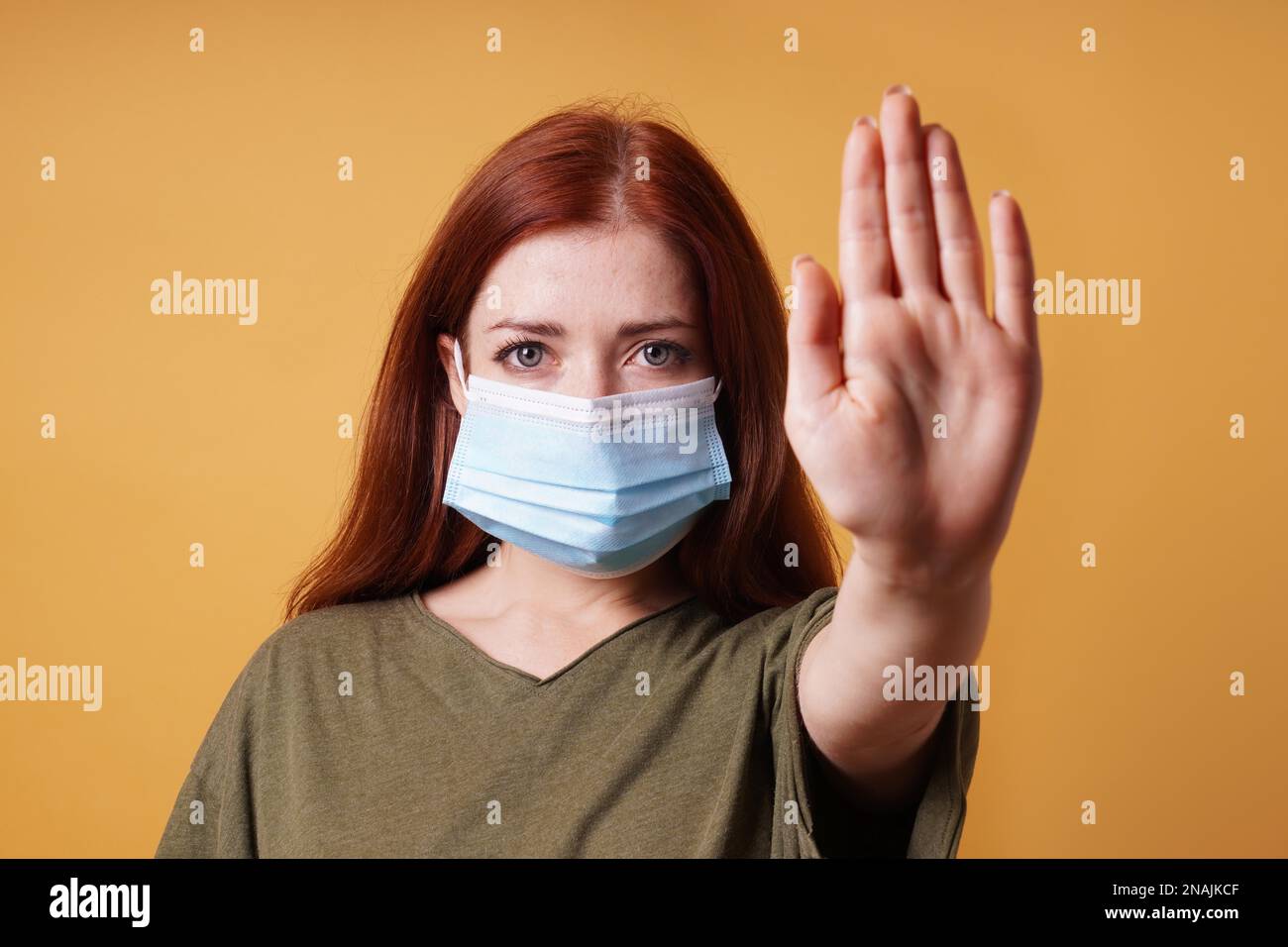 young woman wearing medical face mask making stop gesture with her hand ...