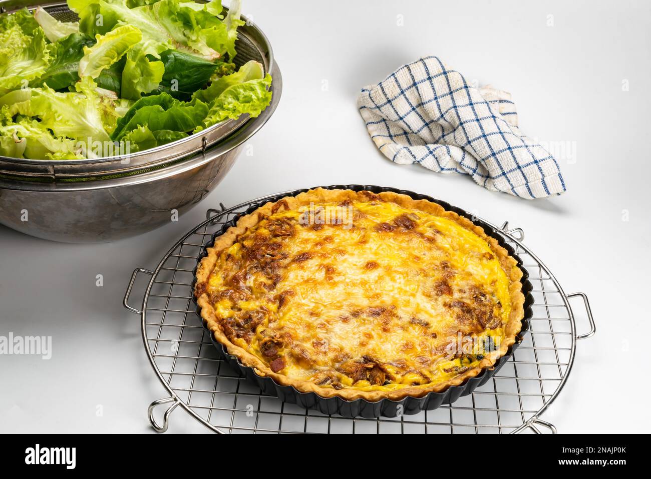 Freshly baked quiche in black metal oven pie baking plate on a metal ...