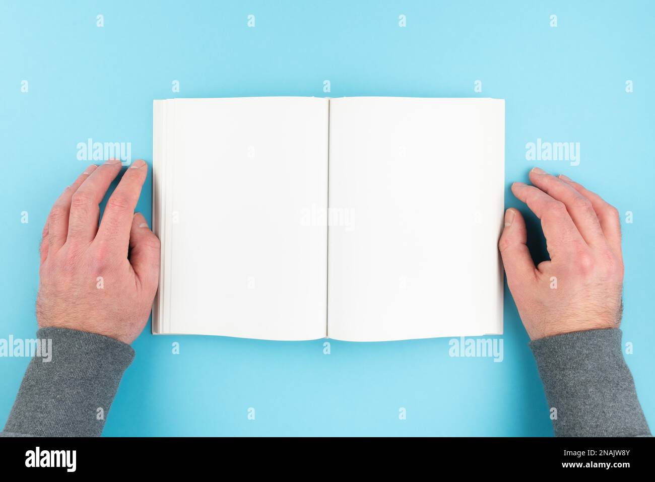 overhead view of person reading book with hands resting on both sides ...