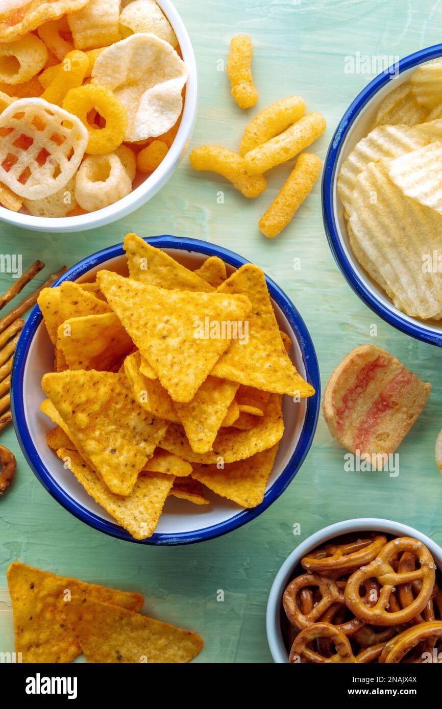 Tortilla chips, salt ptetzels and other salty snacks, overhead flat lay ...