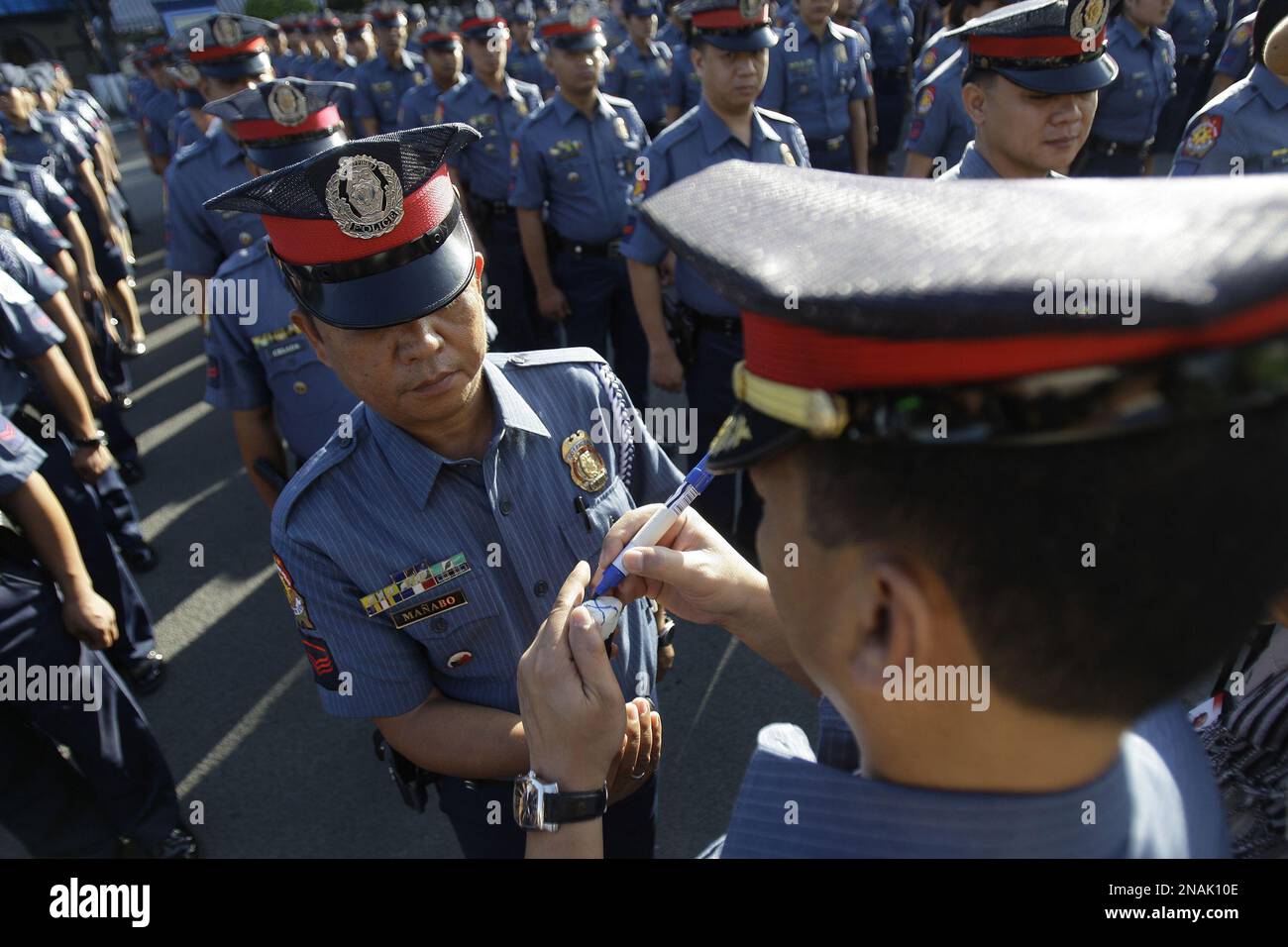 A Filipino police officer marks and signs the tape on the nozzle of a ...