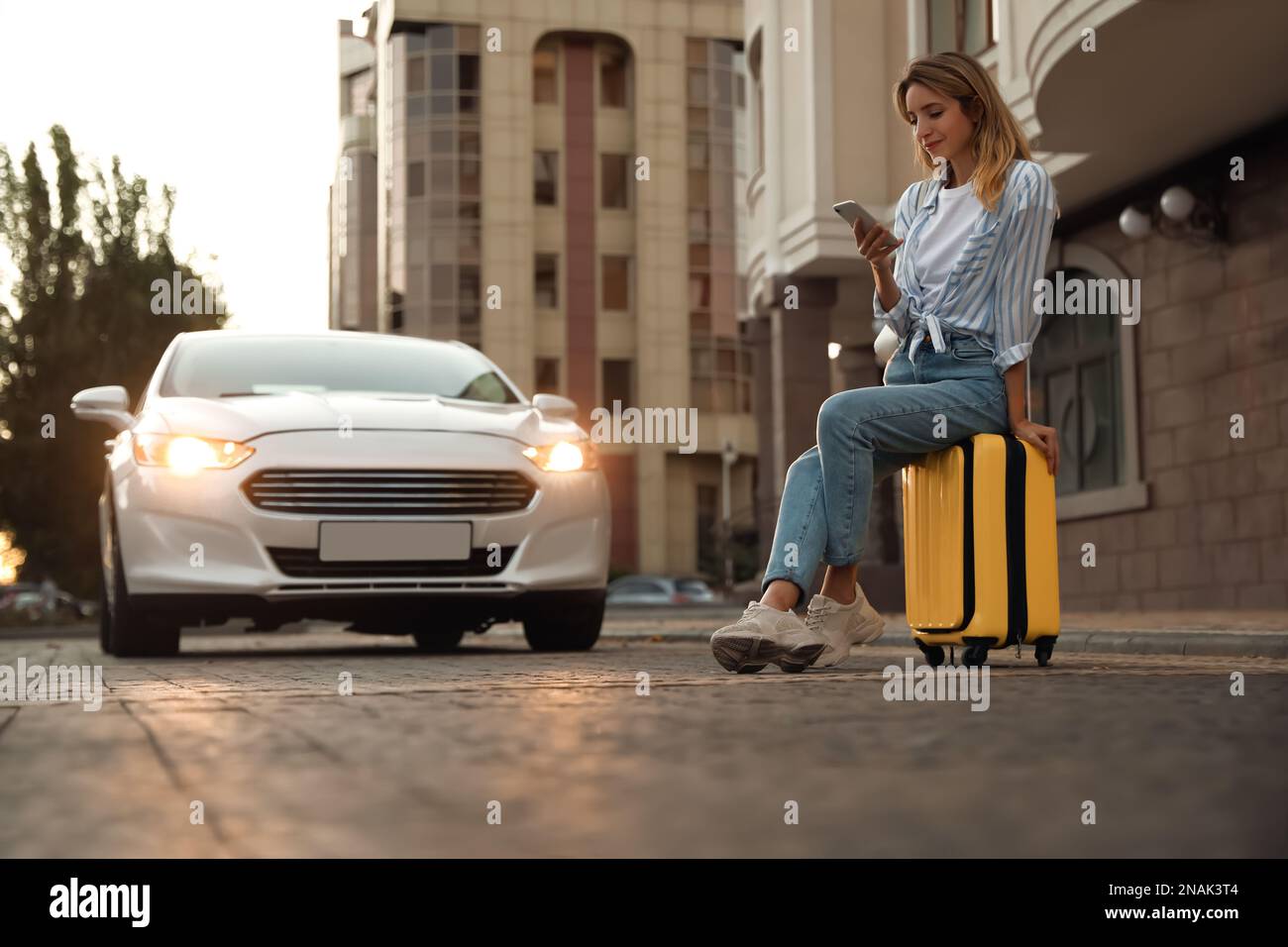 Woman ordering taxi with smartphone on city street Stock Photo - Alamy