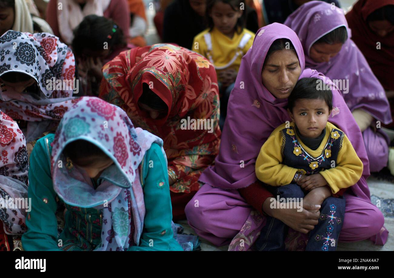 A Pakistani child, right, looks on while being held by her mother as ...