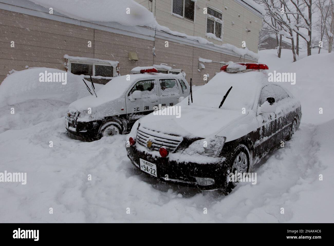 Police cars are parked outside in the snow at the local police station ...