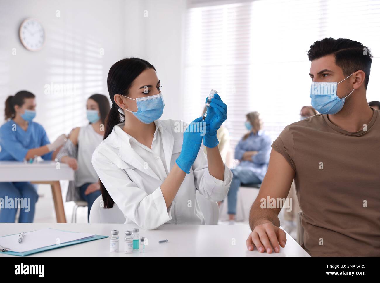 Doctor giving injection to patient while other waiting in line at ...