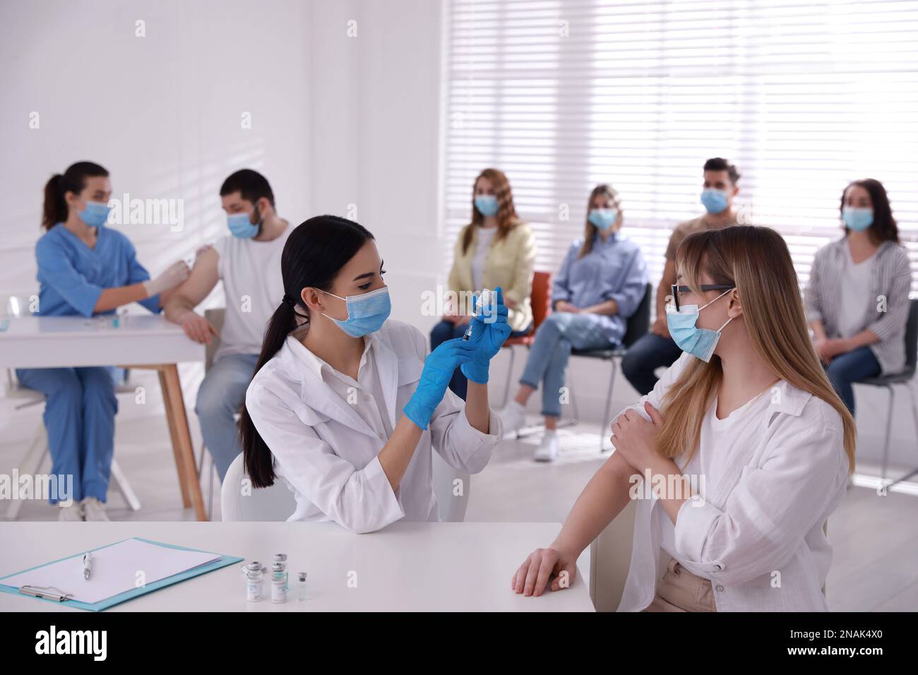 Doctor giving injection to patient while other waiting in line at ...