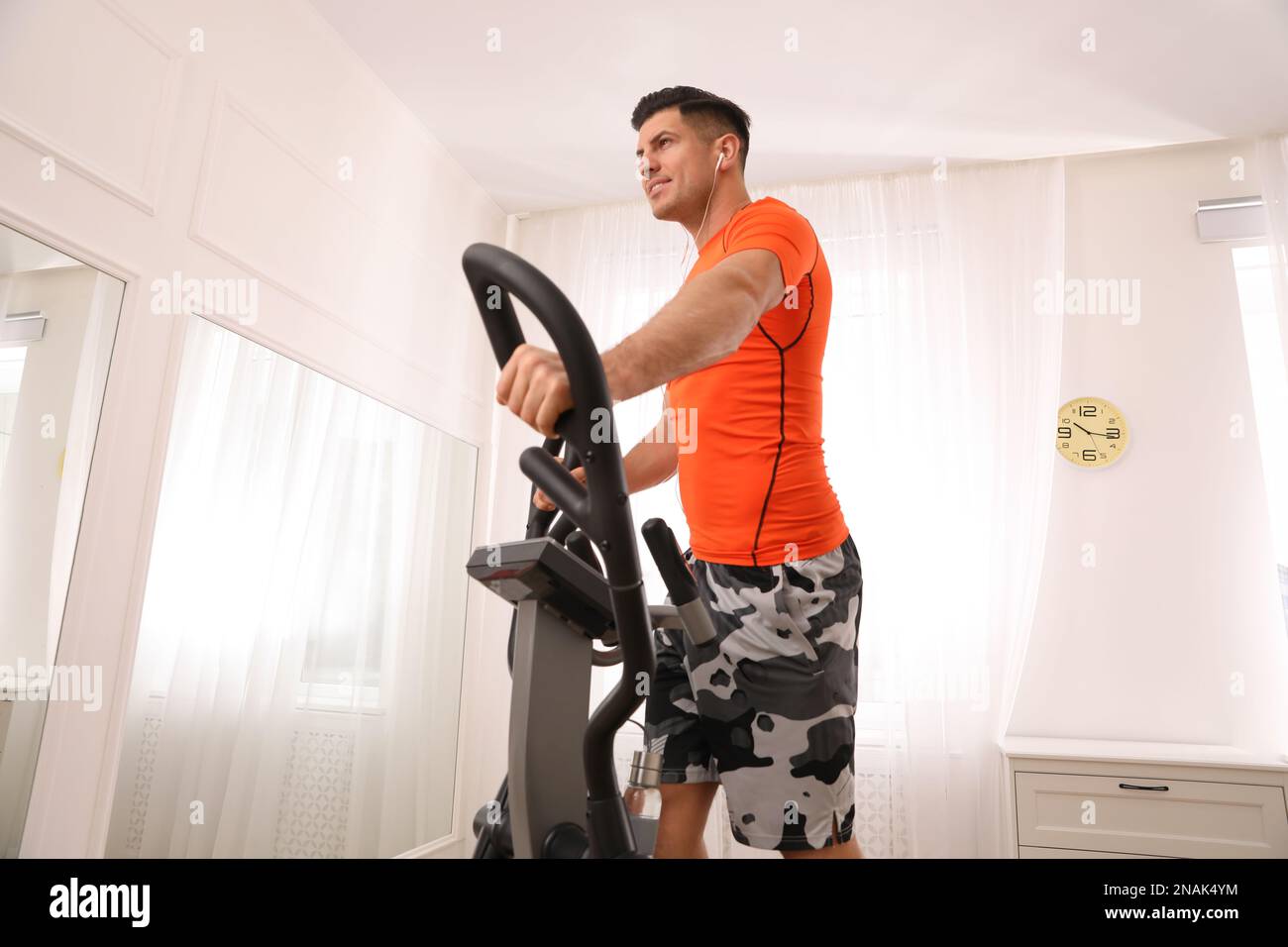 Man using modern elliptical machine at home Stock Photo - Alamy