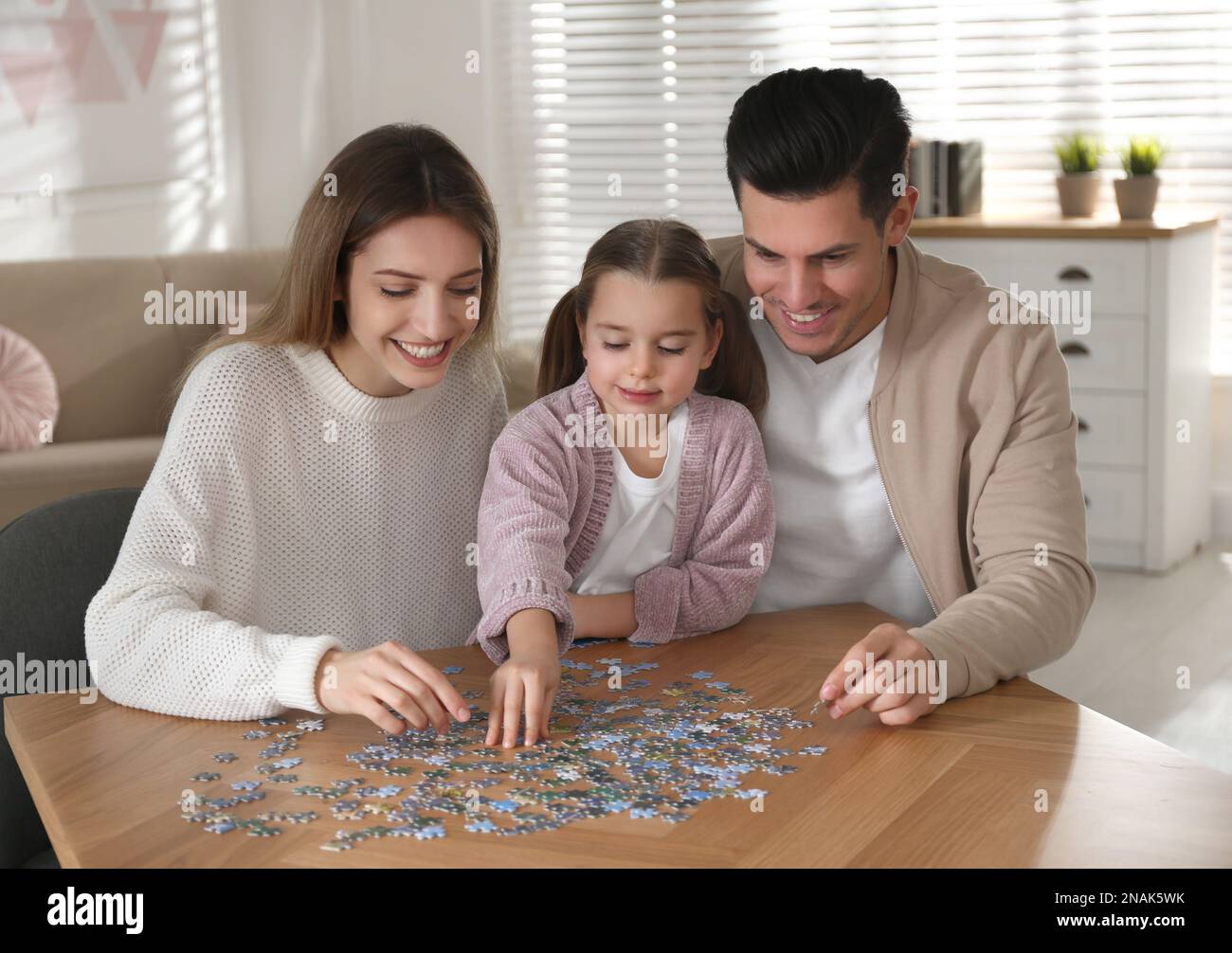Happy family playing with puzzles at home Stock Photo - Alamy