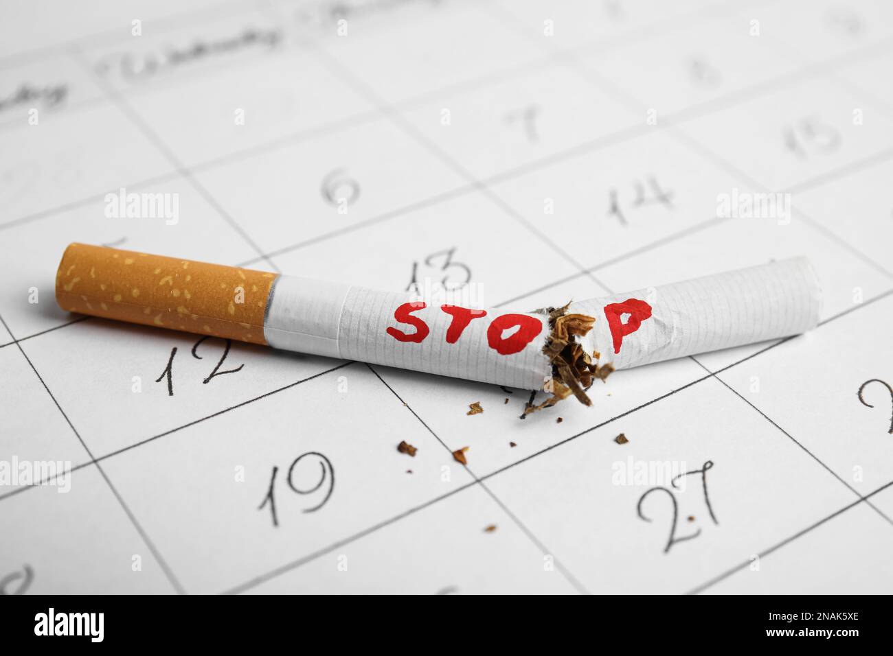 Broken cigarette with word Stop on calendar sheet. Quitting smoking ...