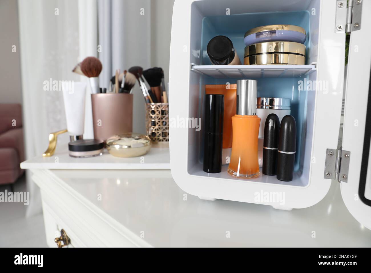 Mini fridge with cosmetic products on white vanity table Stock Photo ...