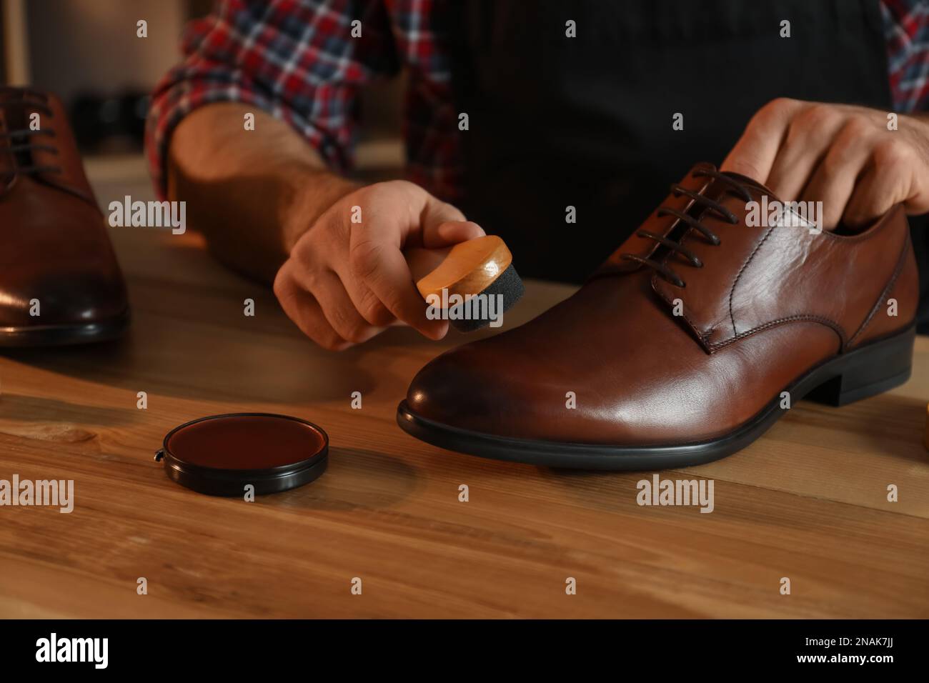 Craftsman taking professional care of brown leather shoes in workshop ...