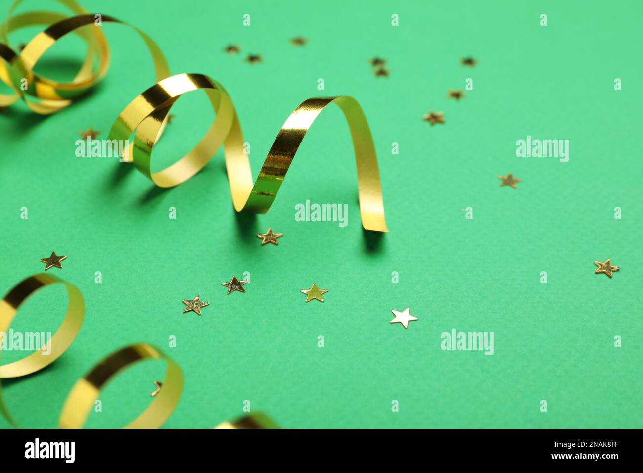 Shiny golden serpentine streamers and confetti on green background ...
