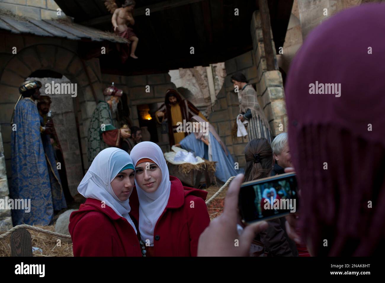 Two Palestinian Muslim women pose for a snapshot in front a nativity ...