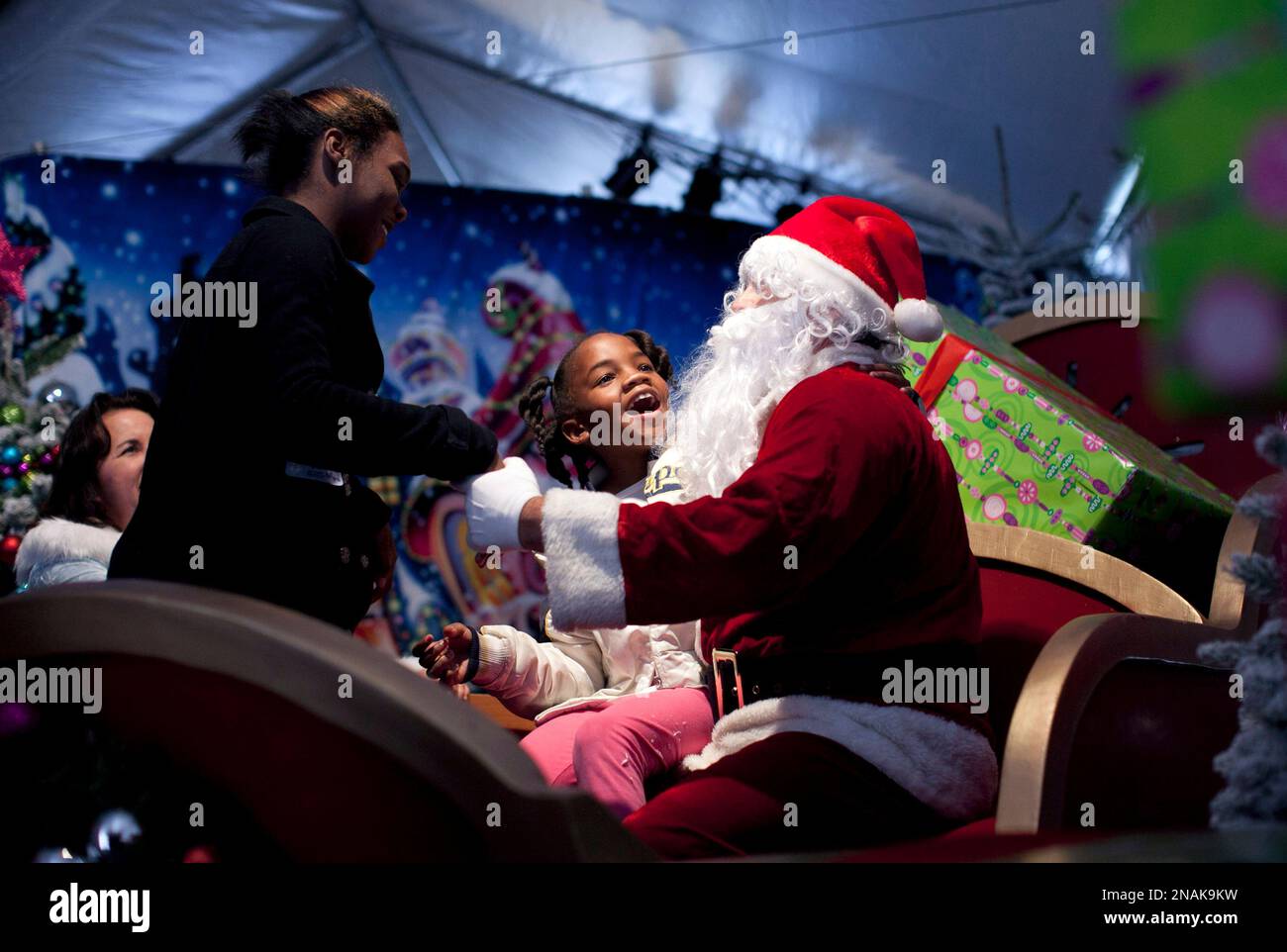 Alisandre Young, center, tells Santa Claus her Christmas wishes at the ...