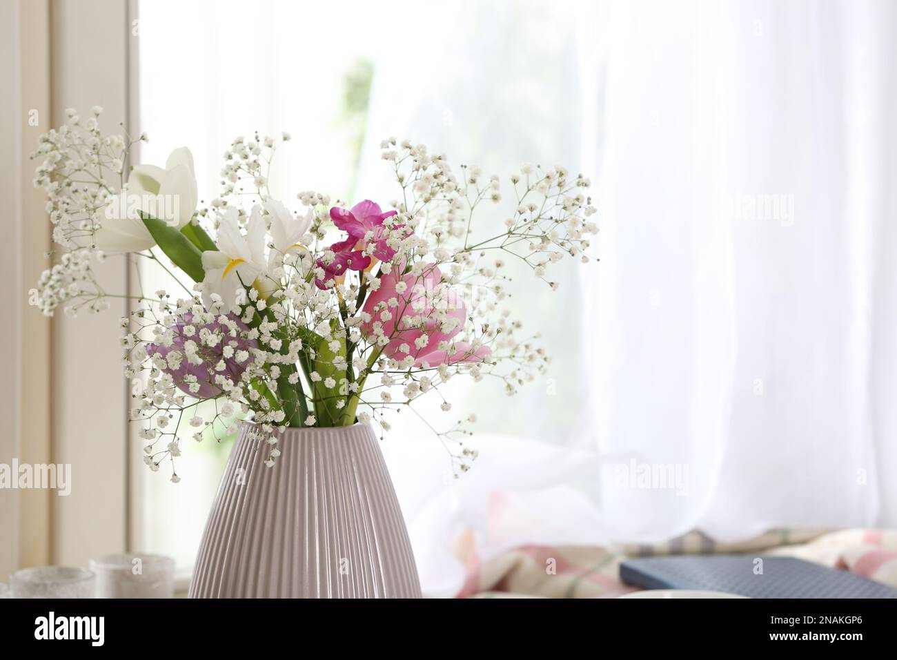 Beautiful fresh flowers near window indoors, closeup. Space for text ...