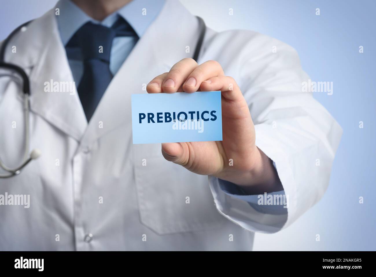 Doctor holding card with word PREBIOTICS on light blue background ...