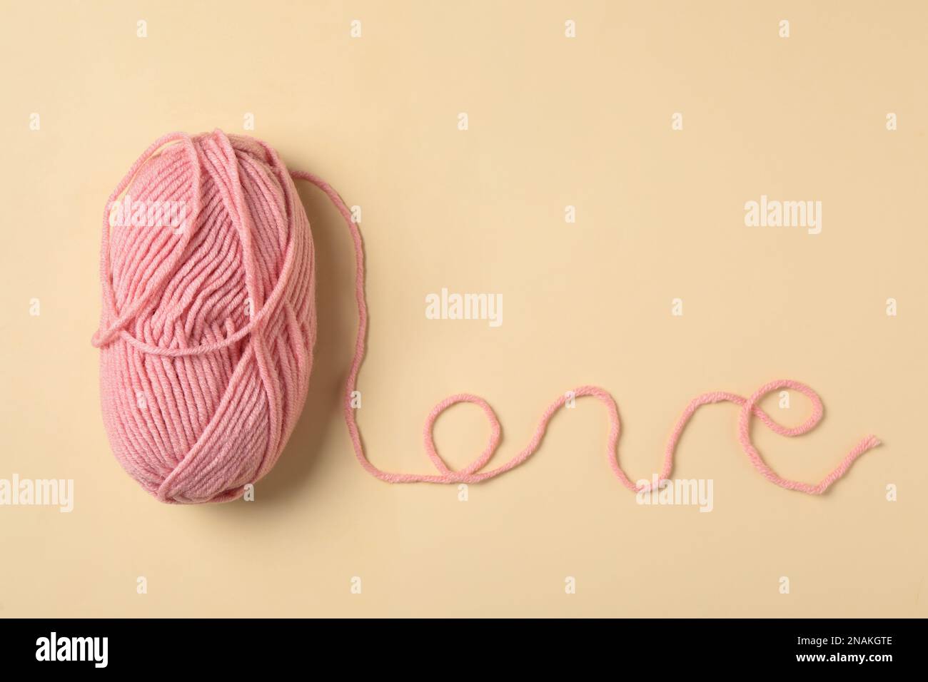 Word Love made with pink thread and woolen yarn on beige background ...