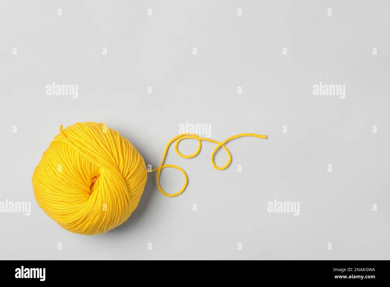 Soft yellow woolen yarn on white background, top view. Space for text ...