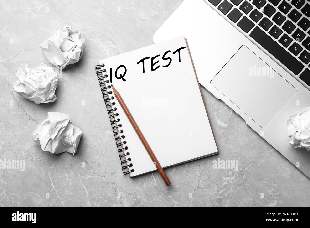 Notebook with text IQ Test and crumpled paper on grey marble table ...