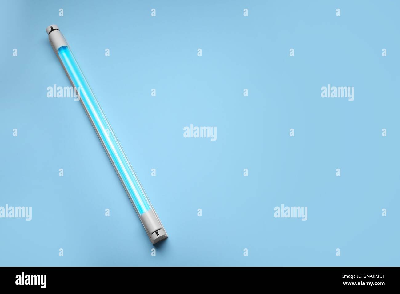 Ultraviolet lamp on light blue background, top view. Space for text ...