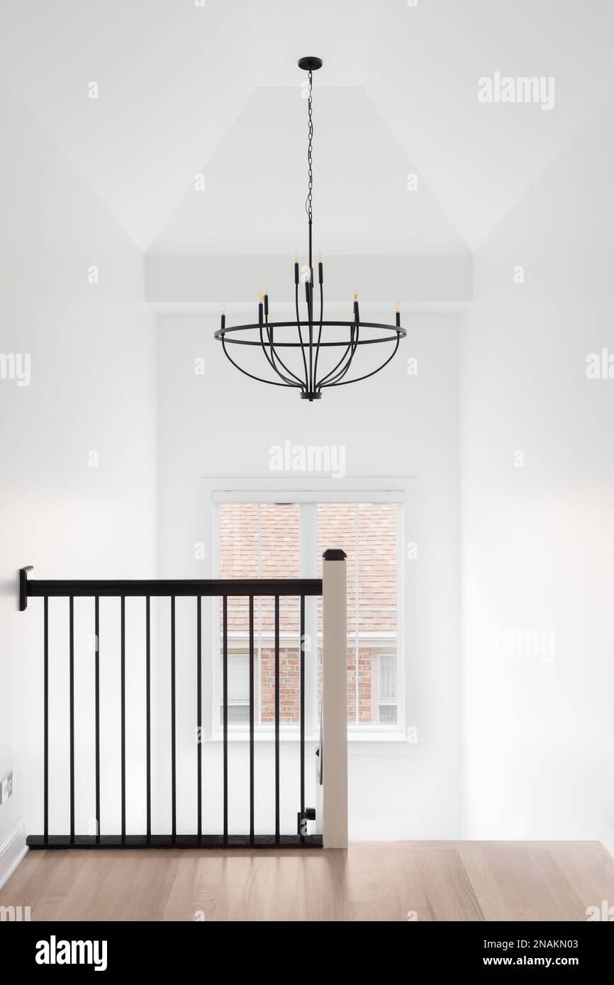 A hallway and staircase with a wrought iron railing, hardwood floor ...