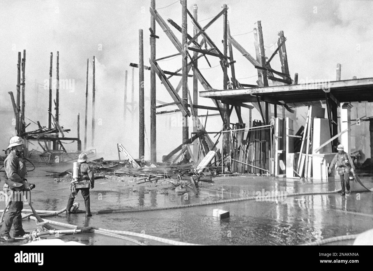 Los Angeles City firemen hose down the skeletal remains of a set inside ...