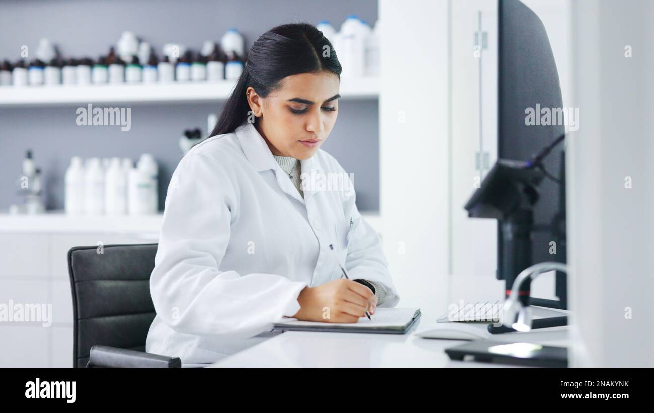Young scientist using a computer and microscope in a lab. Female ...