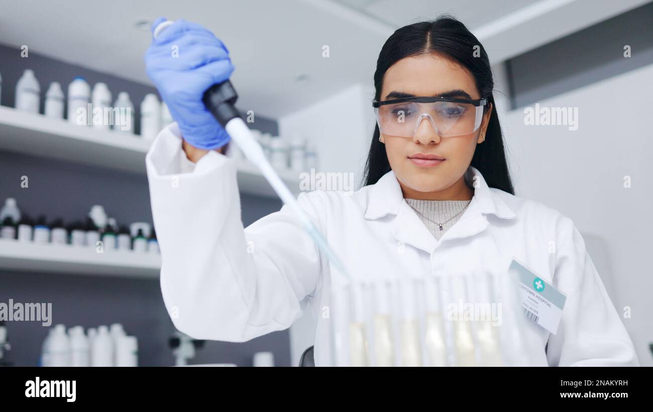 Female scientist experimenting with test tubes and a syringe. One young ...