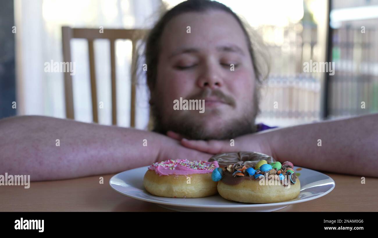 Man in front of donuts on plate. person wanting to eat sugar carb food ...