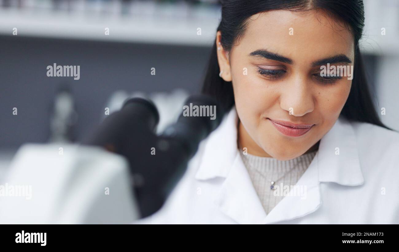 Young scientist using a digital tablet and microscope in a lab. Female ...