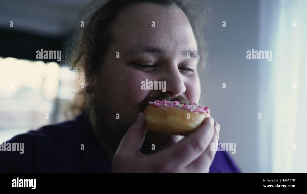 One fat man eating donut. Overweight person taking a bite of junk food ...