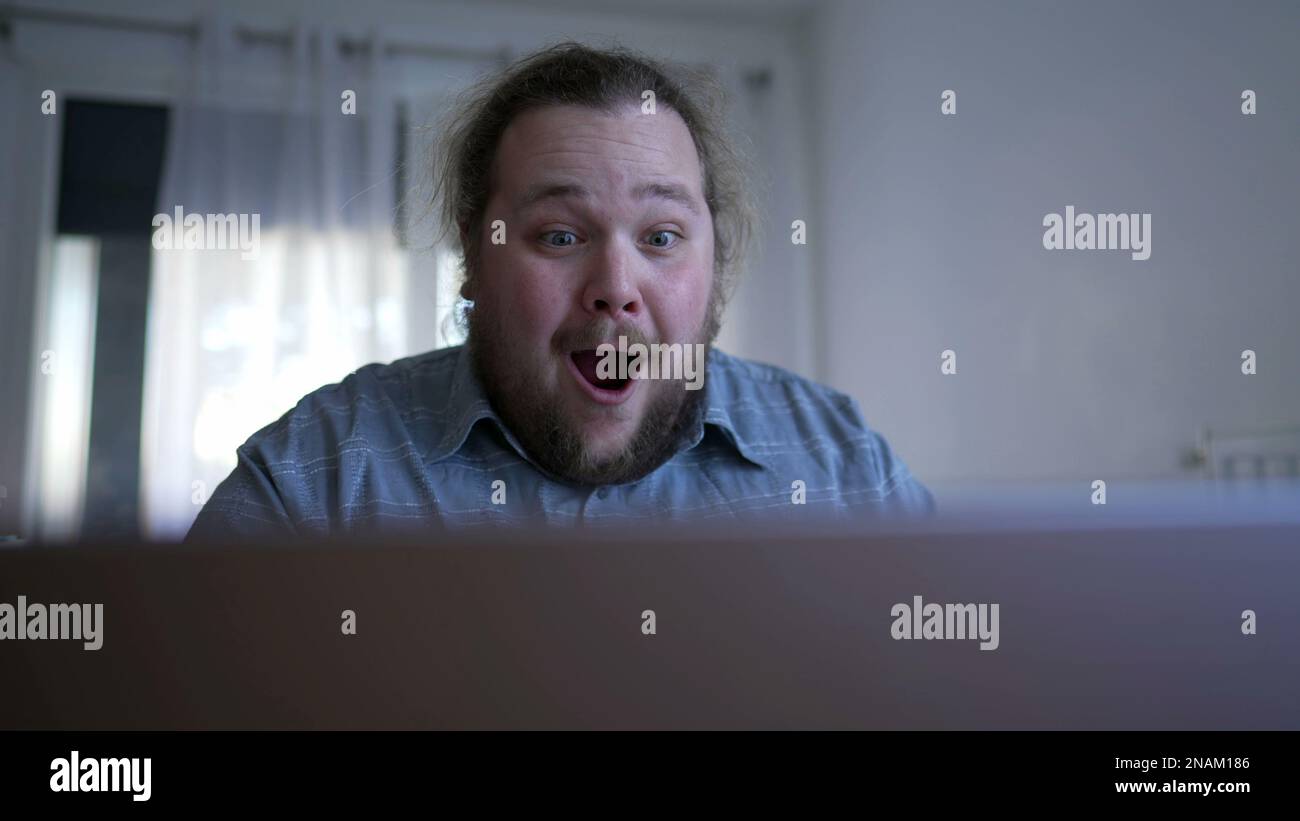 One happy man celebrates success in front of computer. A male chubby ...