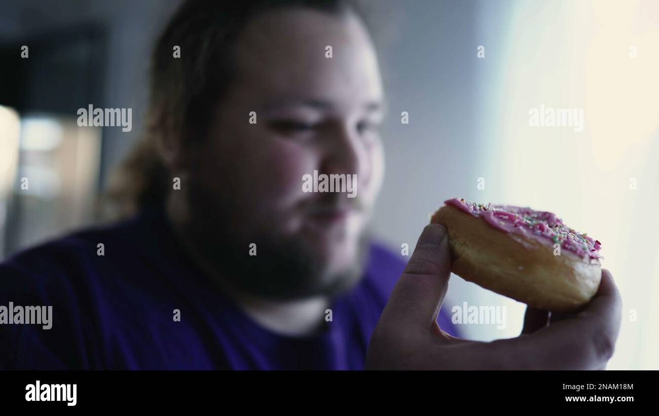 One fat man eating donut. Overweight person taking a bite of junk food ...