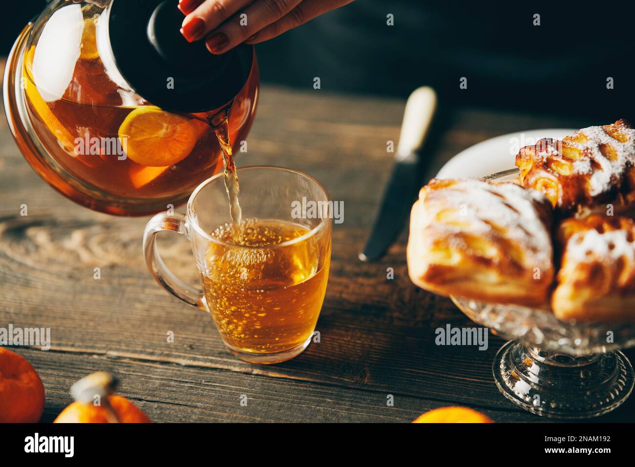Female hand holding glass teapot and pouring hot aromatic tea to the ...