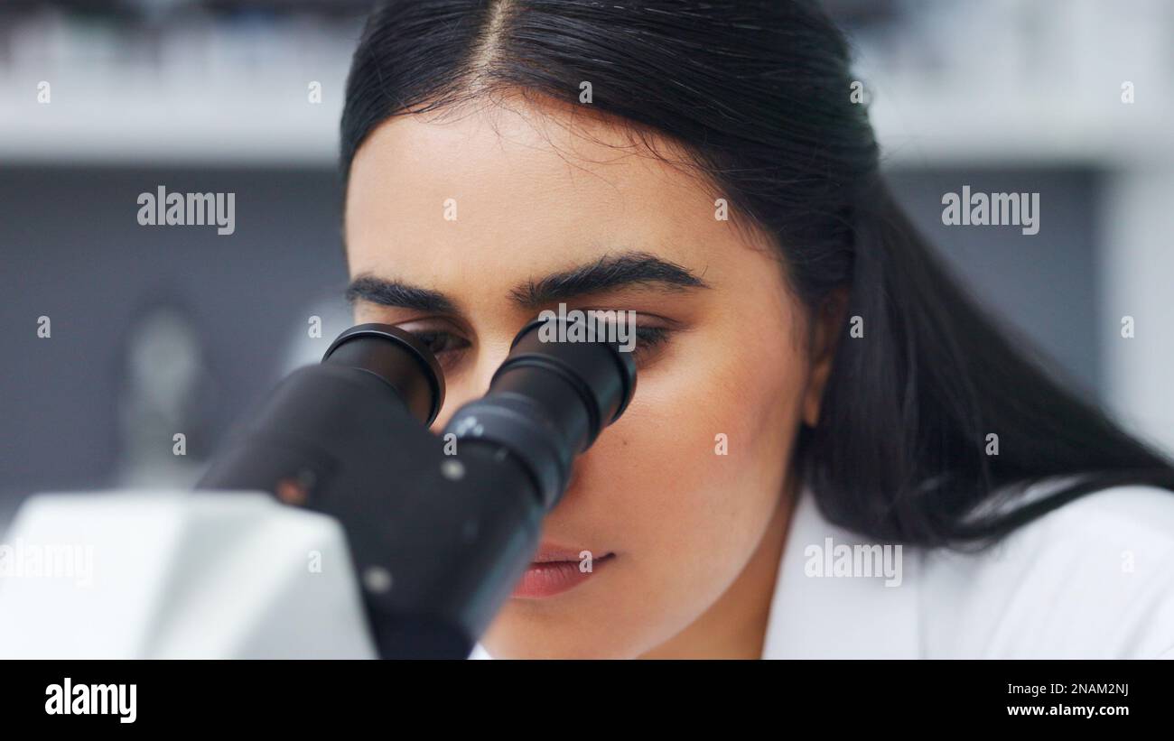 Female scientist using a microscope in a research lab. Young biologist ...